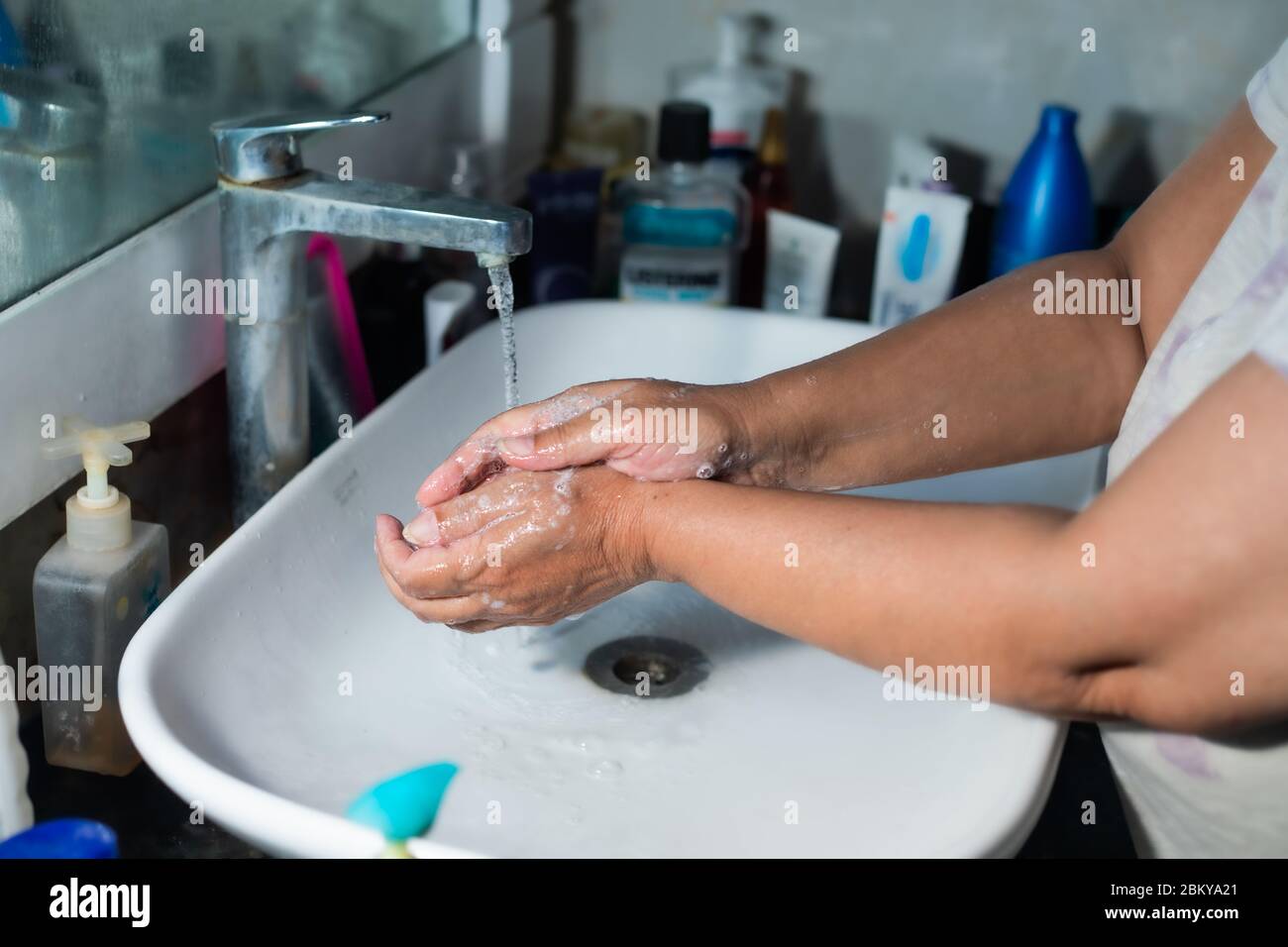 Adult washing hands and arms properly with alcohol soap under the sink ...