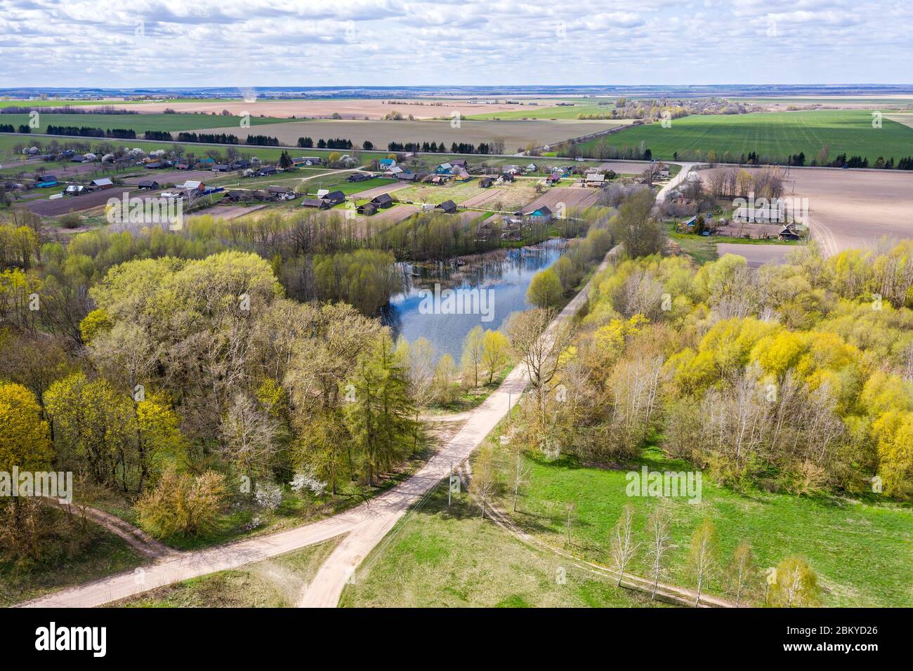 aerial view of a small rural village among green fields in sunny day ...