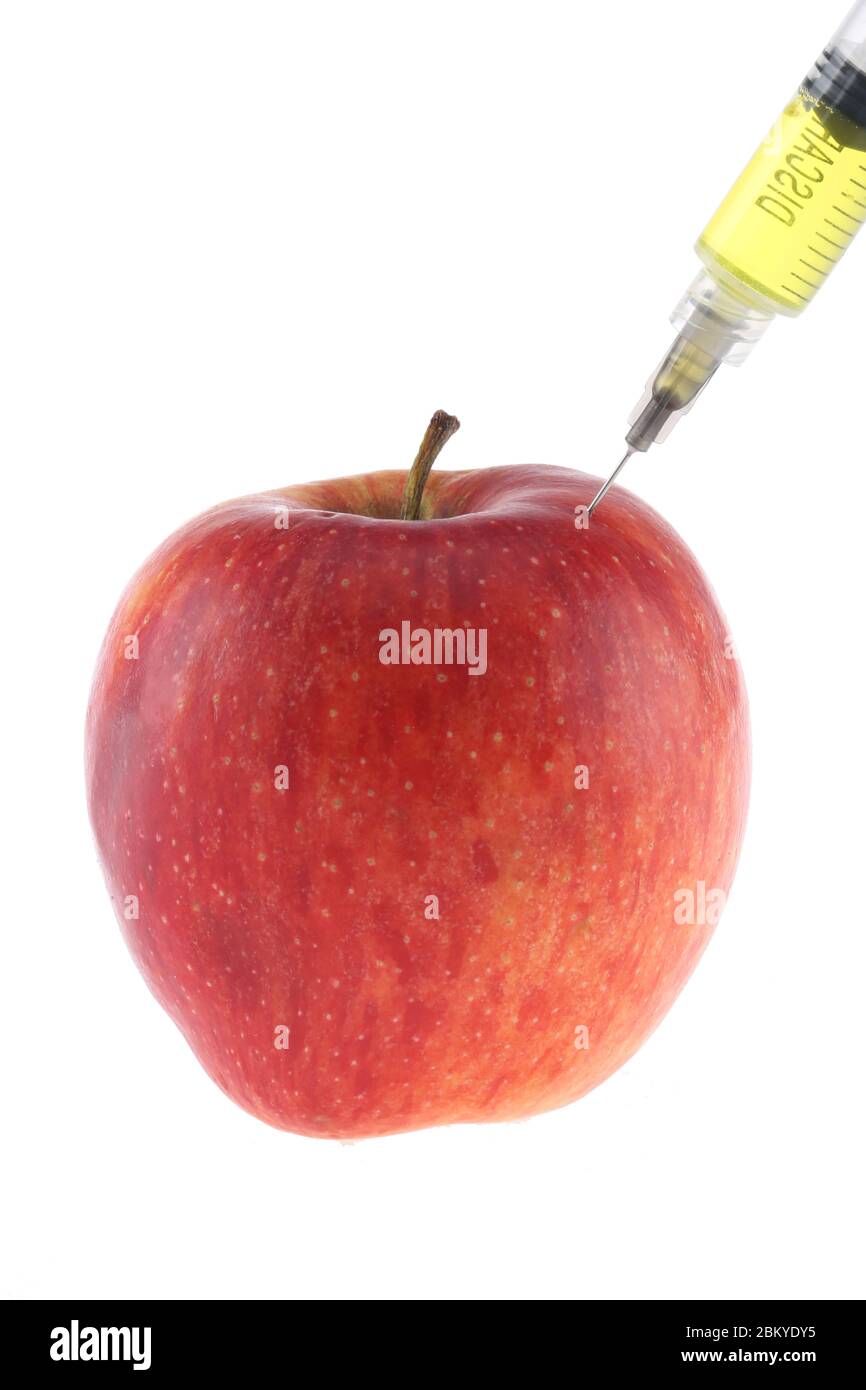 Injection into an apple. A hand in a medical glove with a syringe on a ...