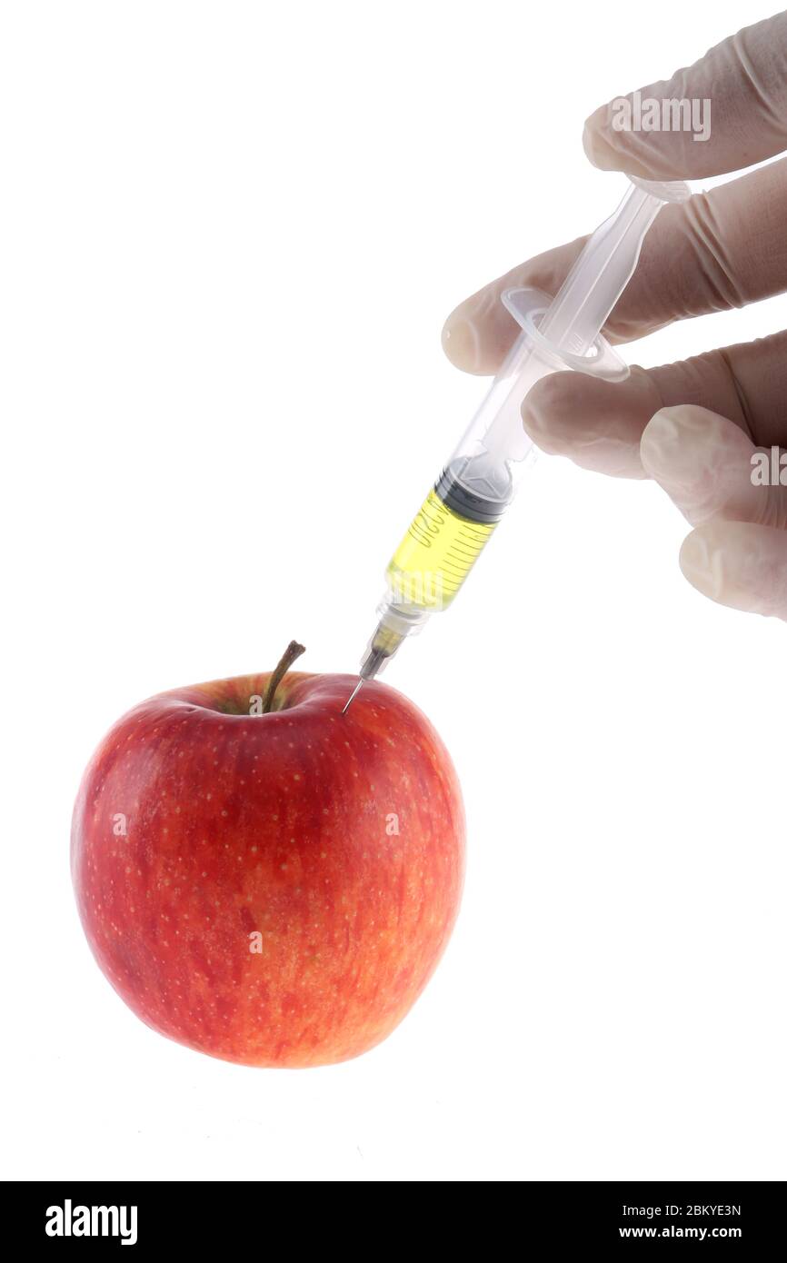 Injection into an apple. A hand in a medical glove with a syringe on a ...