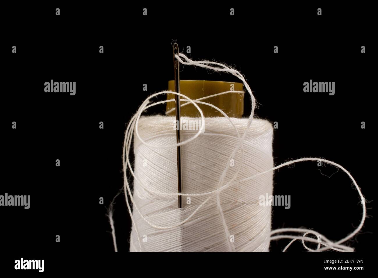 Needle and white cotton, tangled yarn on roll for sewing. Thread used ...