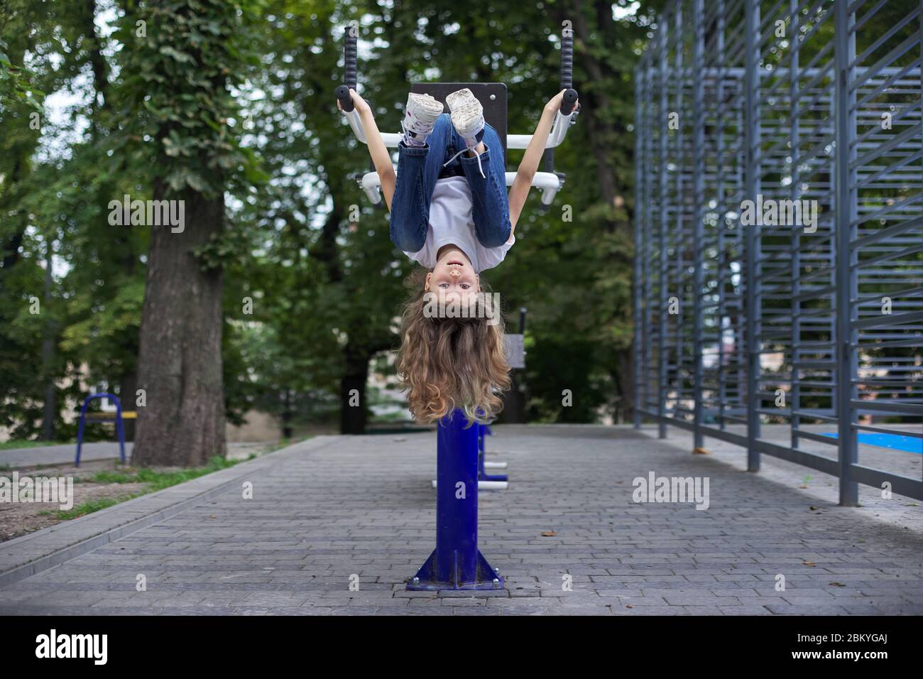 Child girl on sports outdoor simulator, hanging upside down Stock Photo ...