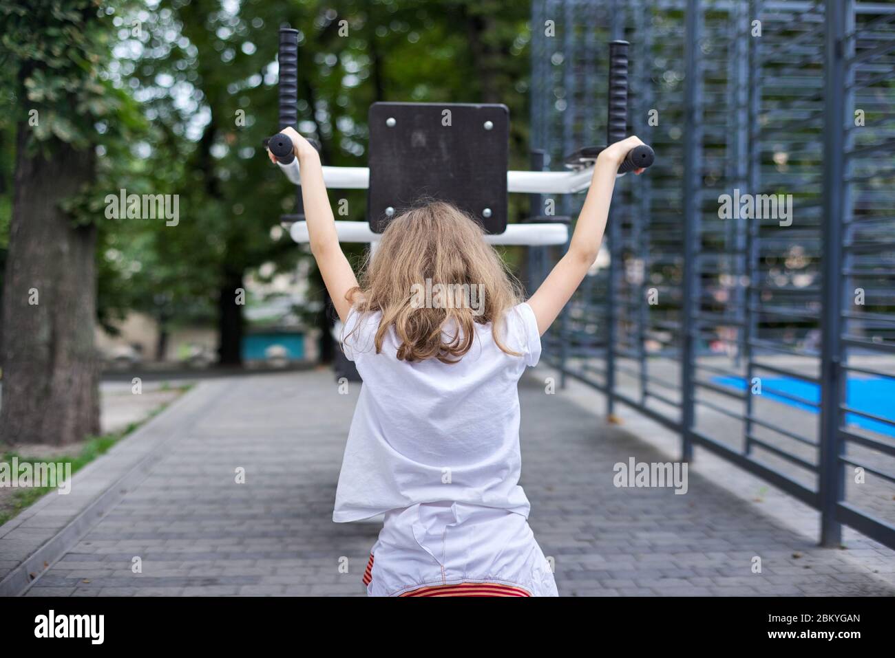 Child girl on sports outdoor simulator, back view Stock Photo - Alamy