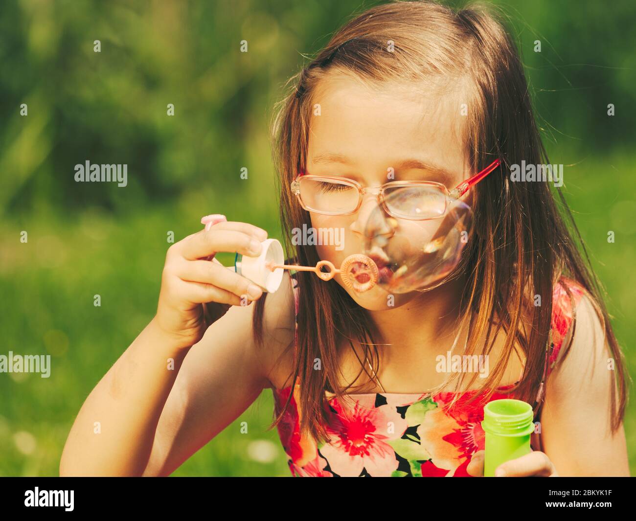 Little girl child blowing soap bubbles outdoor. Kid having fun in park ...