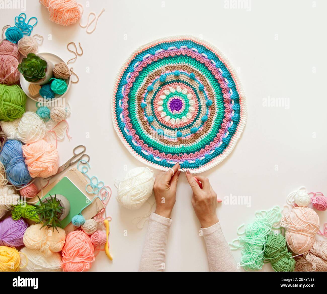 Female hands knitting round mandala with color wool, on a white ...