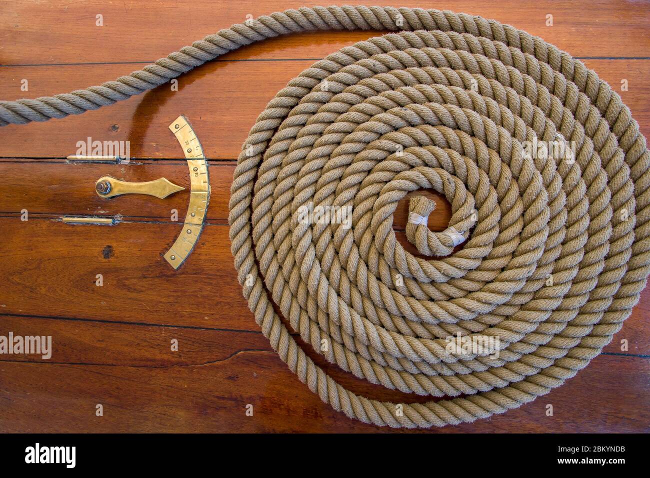 Ship coil on a wooden surface and a brass arrow with a degree scale ...