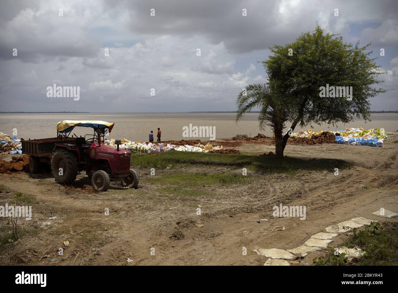 A tractor, sacks and construction workers at a Rupnarayan river-erosion ...