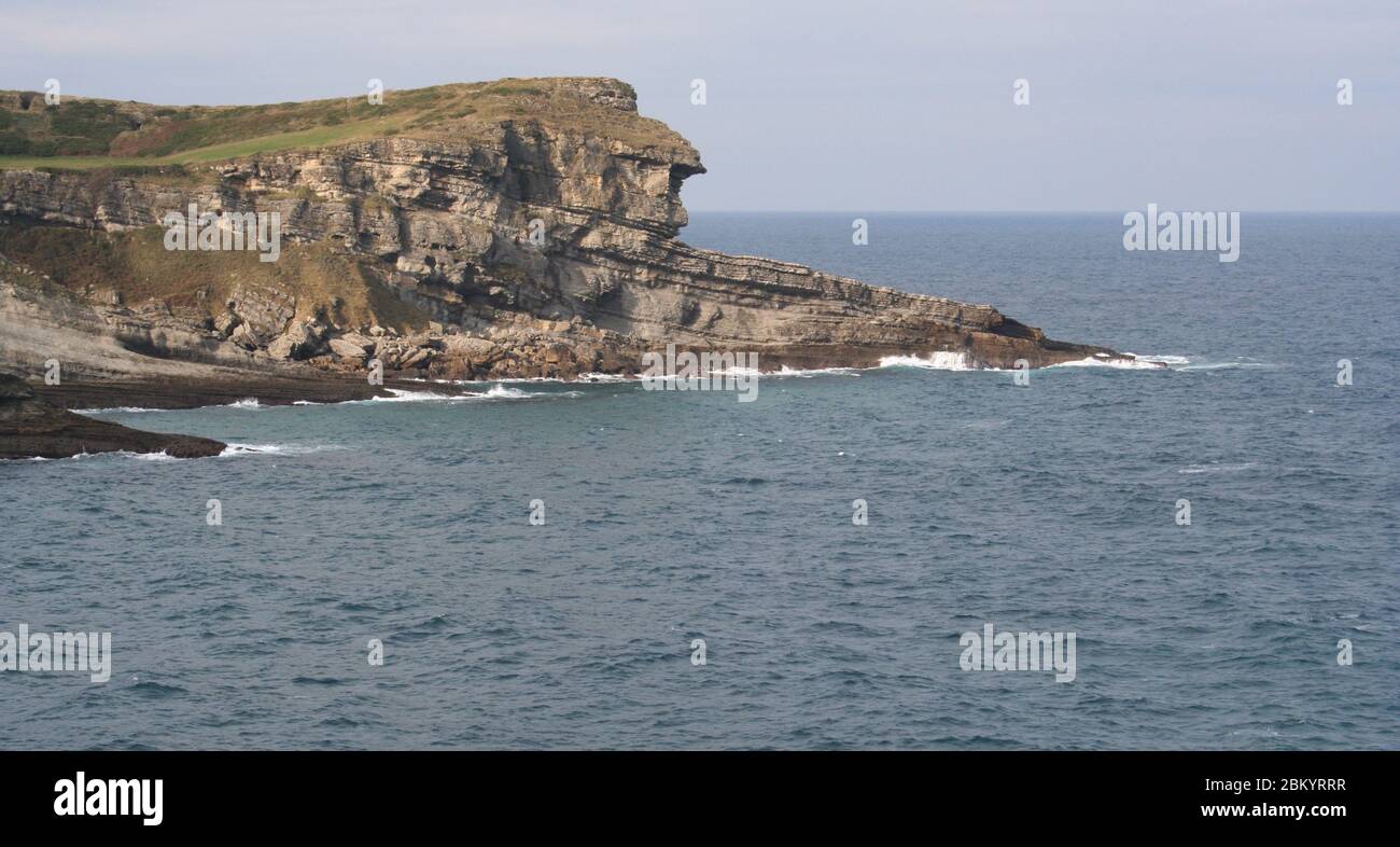 Coastal scene of sloping layered rocks into sea in sun Santander ...