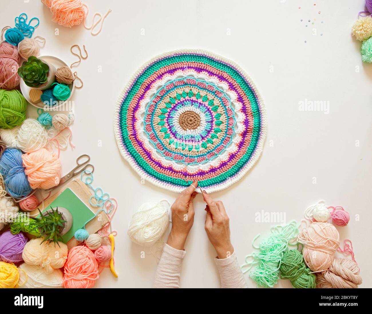 Female hands knitting round mandala with color wool, on a white ...