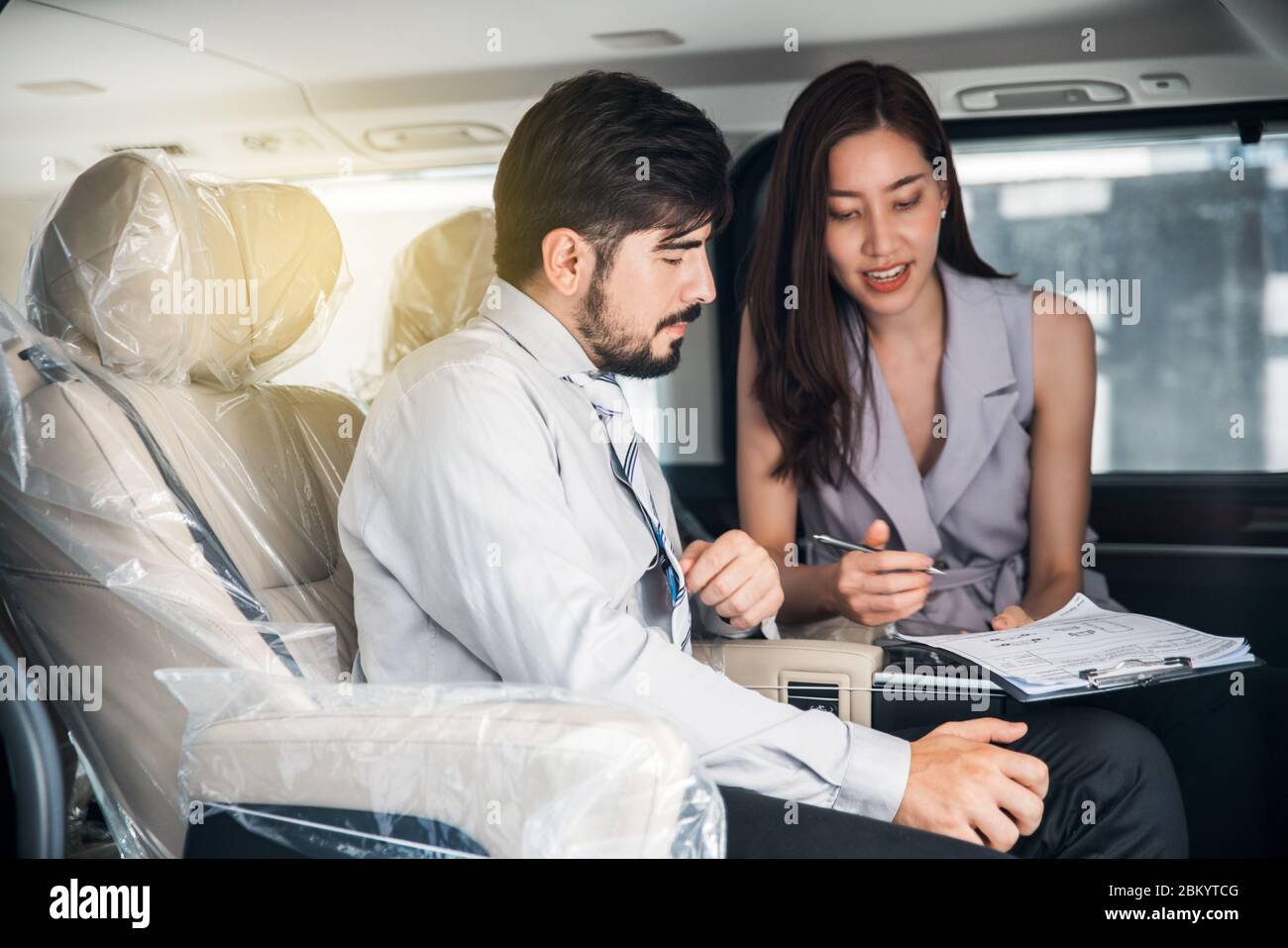 Car Dealership. The Asian Salesman (woman) checking the list with the ...