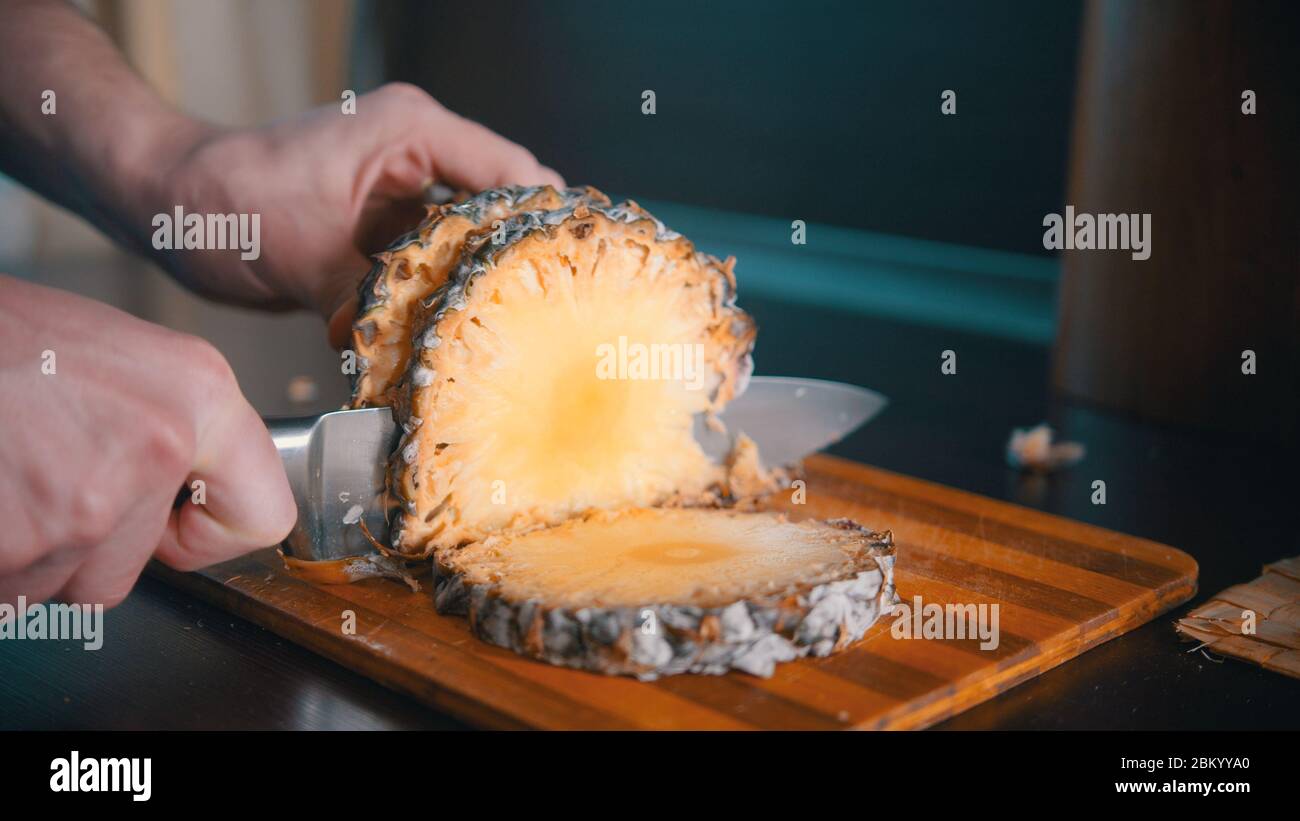 Cutting ripe pineapple with a sharp knife. Mid shot Stock Photo - Alamy