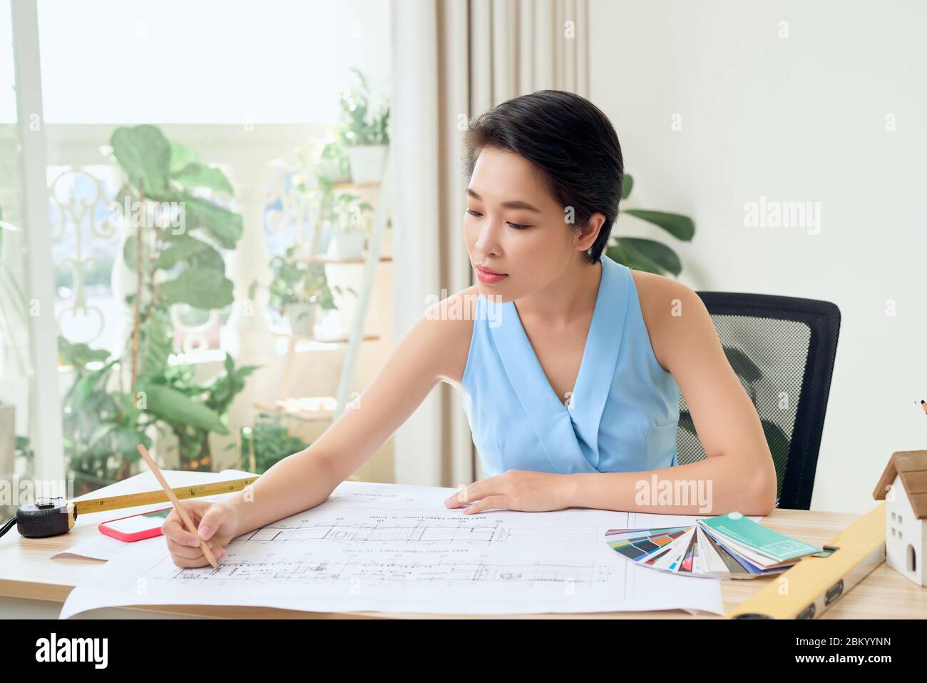 Asian Female architect working at home.She looking blueprints Stock ...