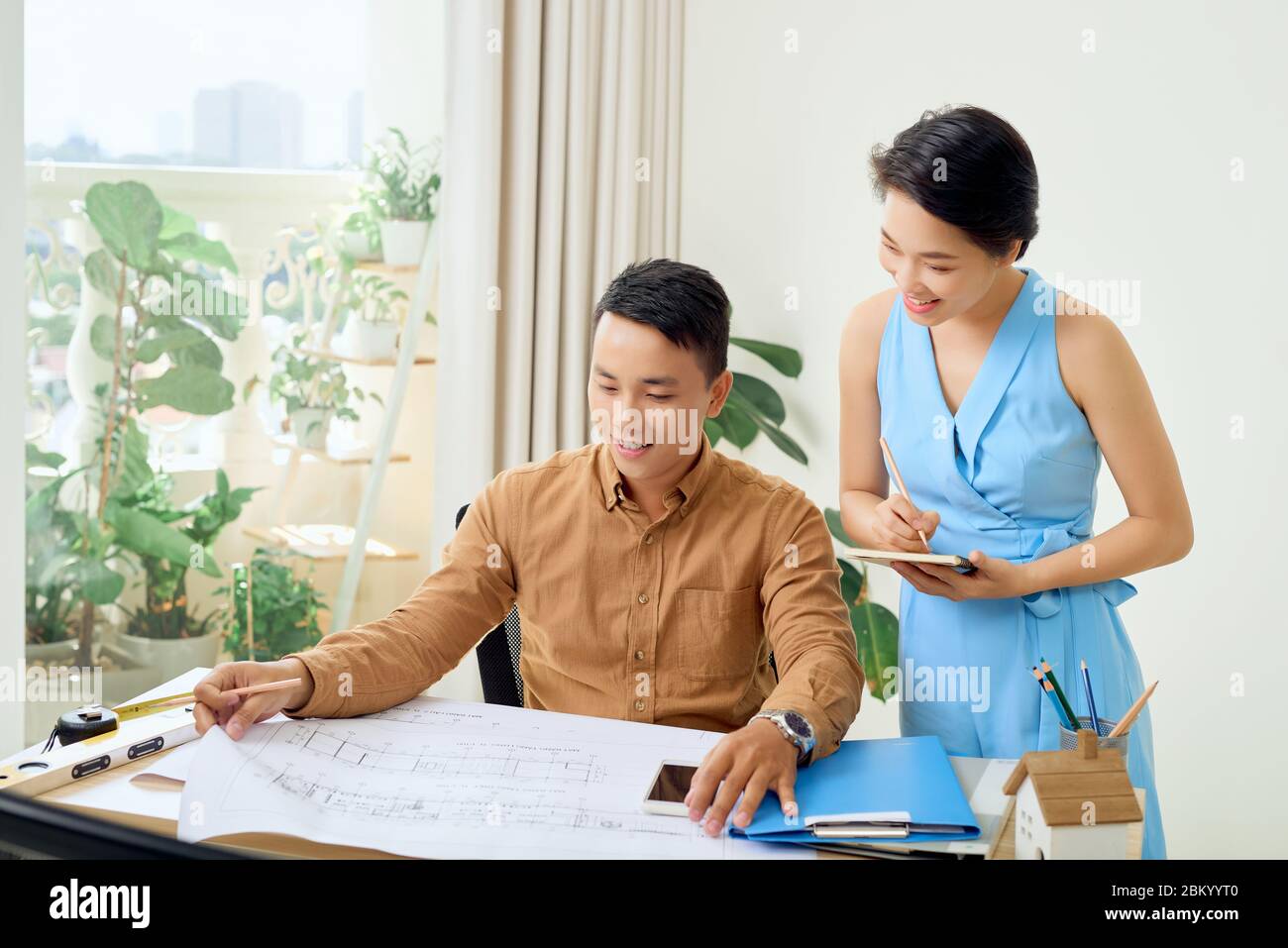 Architects man and woman studying their project with blueprint Stock ...