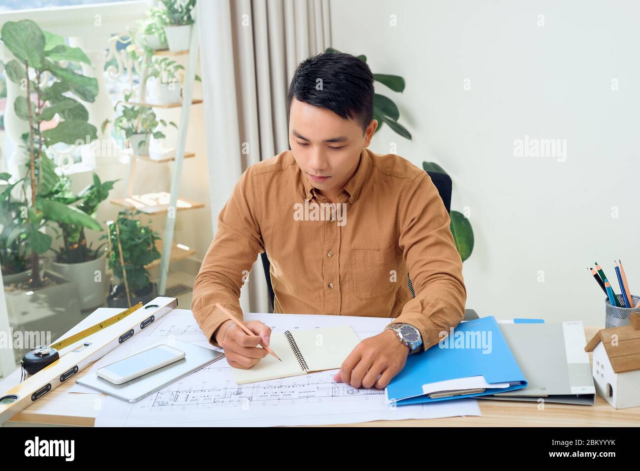 Young Asian Male Architect Studying Plans In Office Stock Photo - Alamy