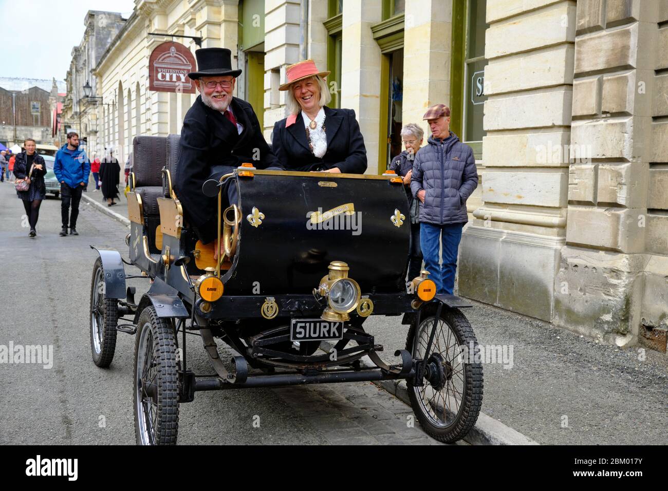 Senior couple traveling in a vintage Victorian car on the streets of ...