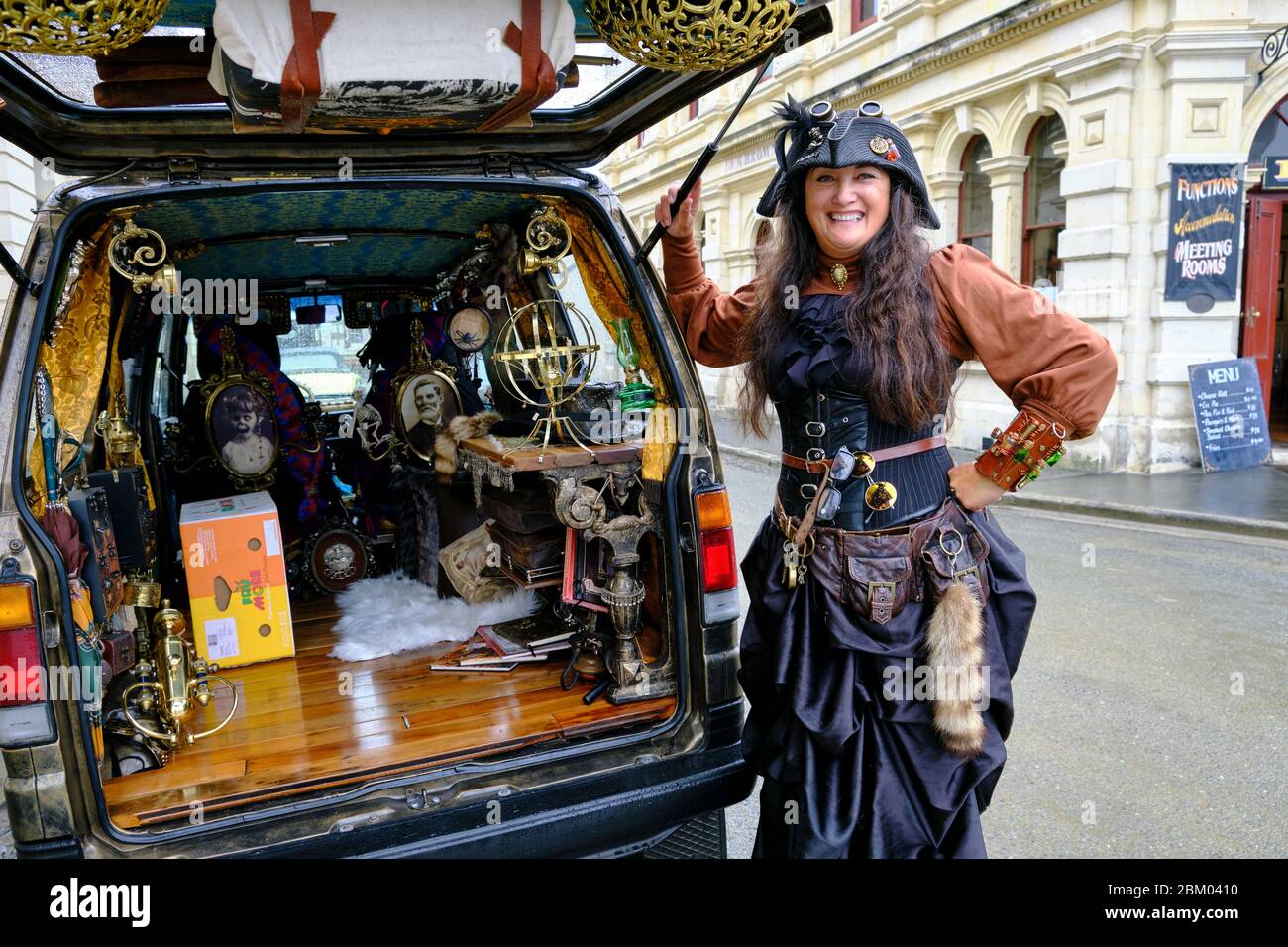 Portrait of a woman dressed in the steampunk style, next to her van ...