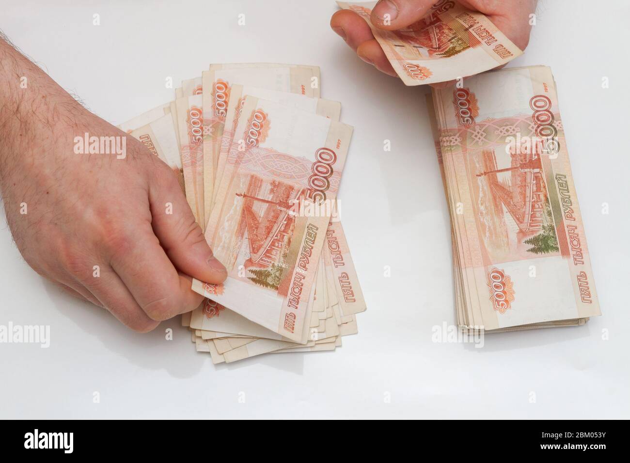 A man's hand counts and shifts a large number of five thousand rubles ...