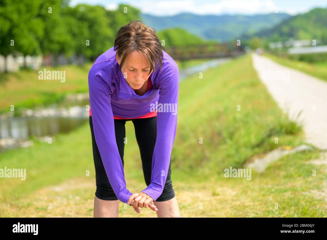 Woman doing stretching exercises before jogging standing alongside ...