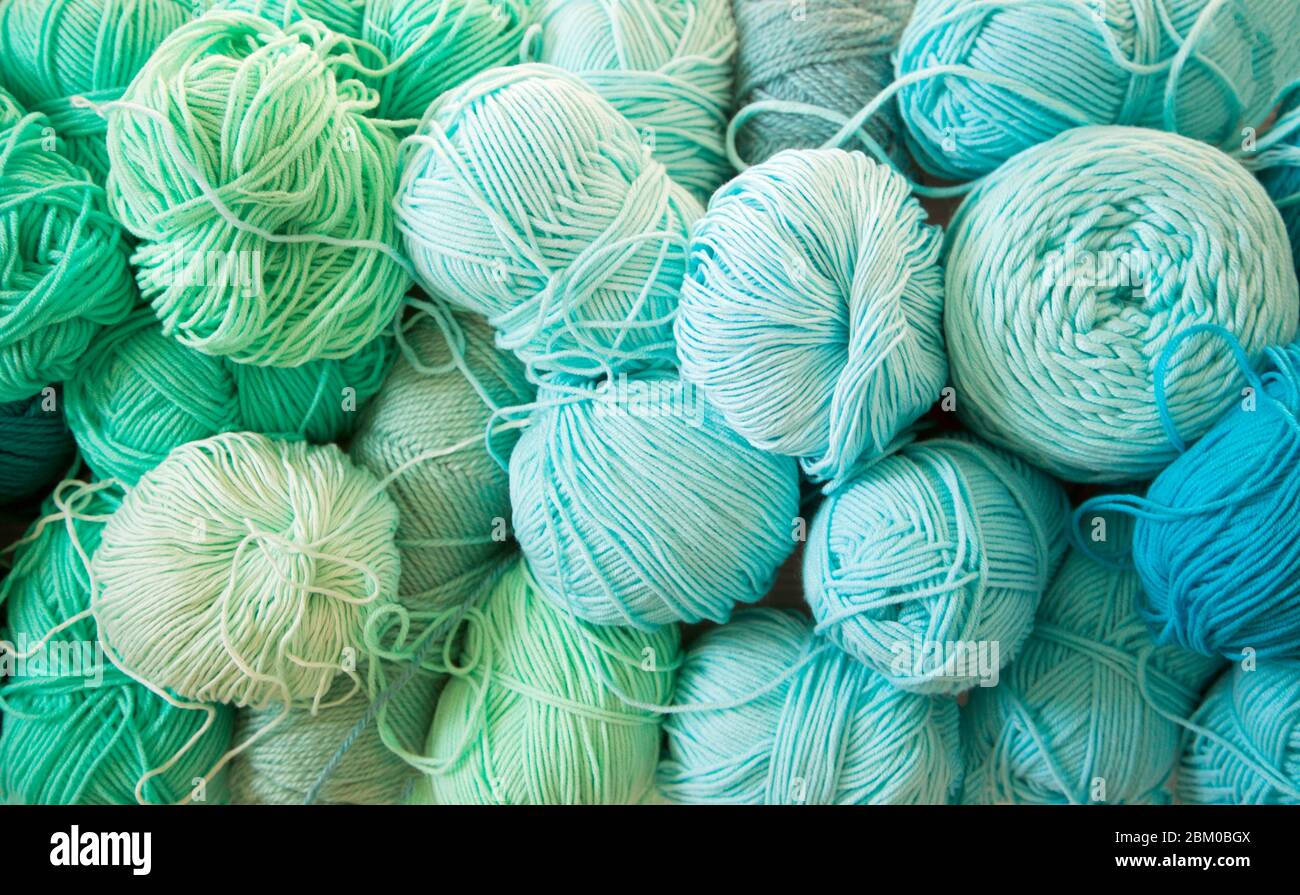 Yarn of green, turquoise, aquamarine and blue colors. White wood ...