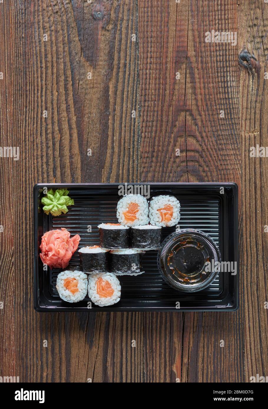 salmon sushi rolls in plastic box on wooden table, top view, food ...