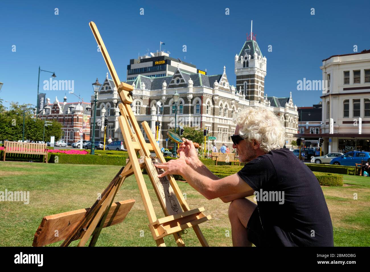 Man doing a pyrography using a magnifying glass in the gardens of ...