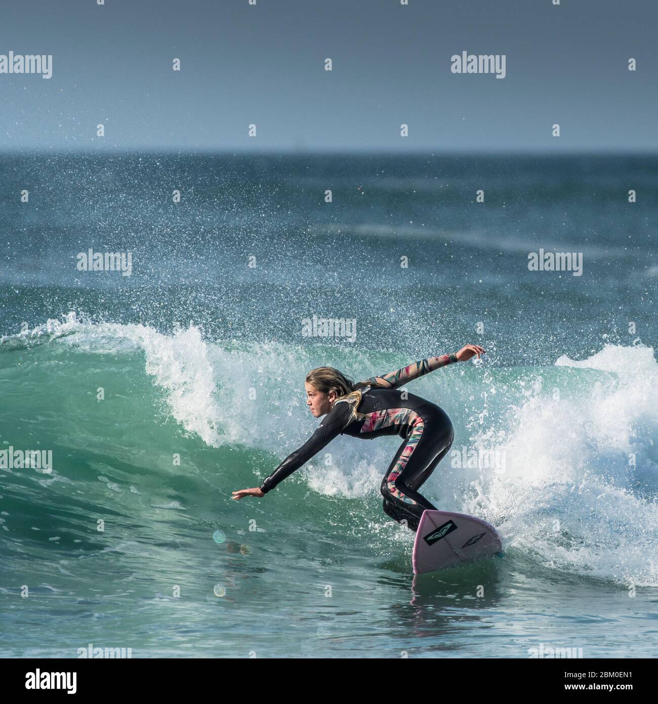 A teenage female surfer surfing at Fistral in Newquay in Cornwall Stock ...