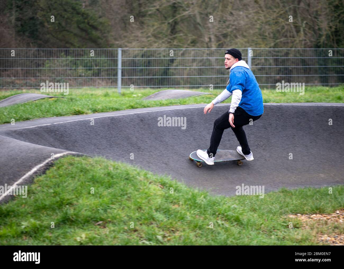 Side view of young focused man in warm sportswear and hat riding on ...