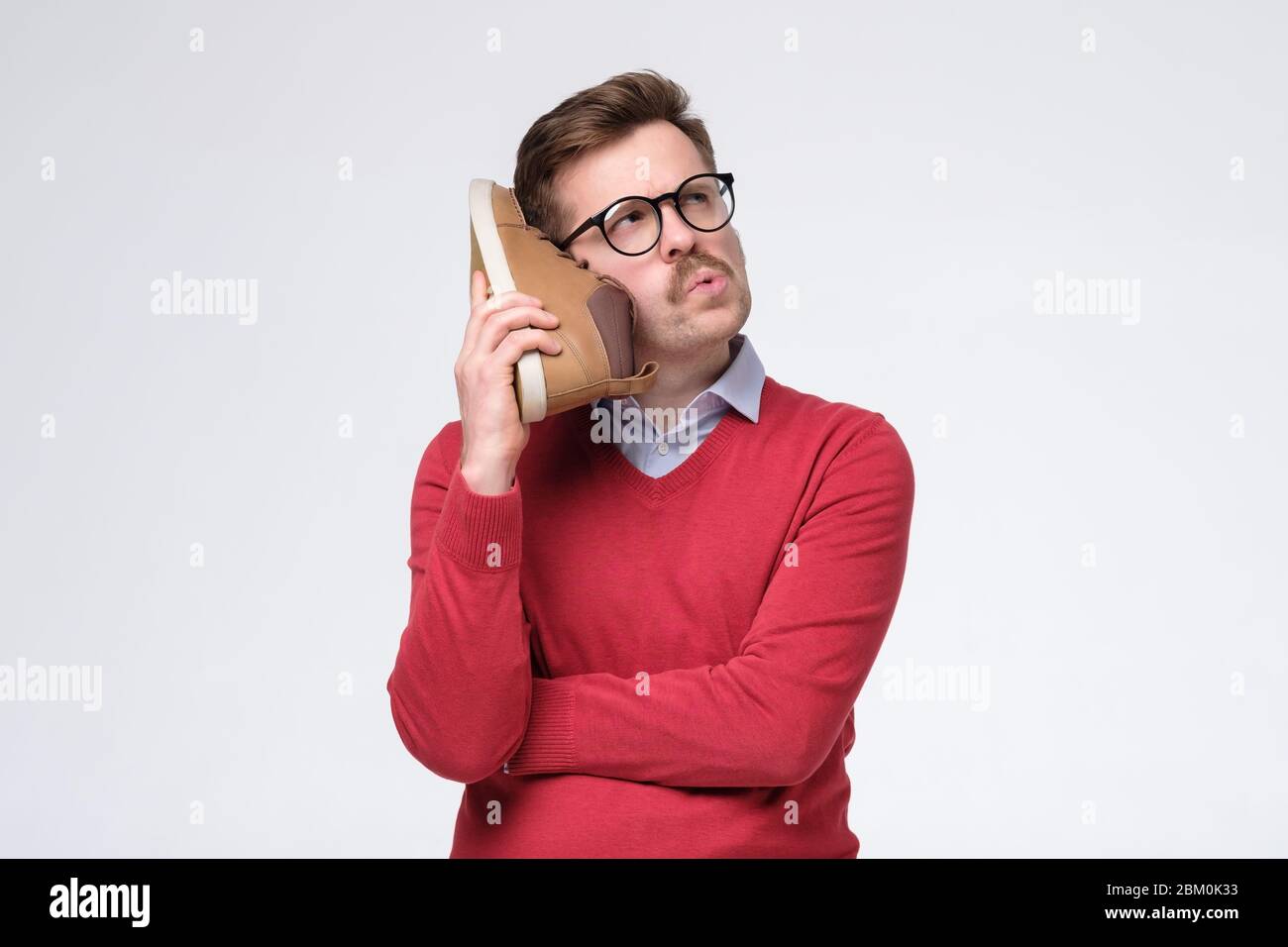 Crazy business man pretending he is speaking on phone using new boot ...