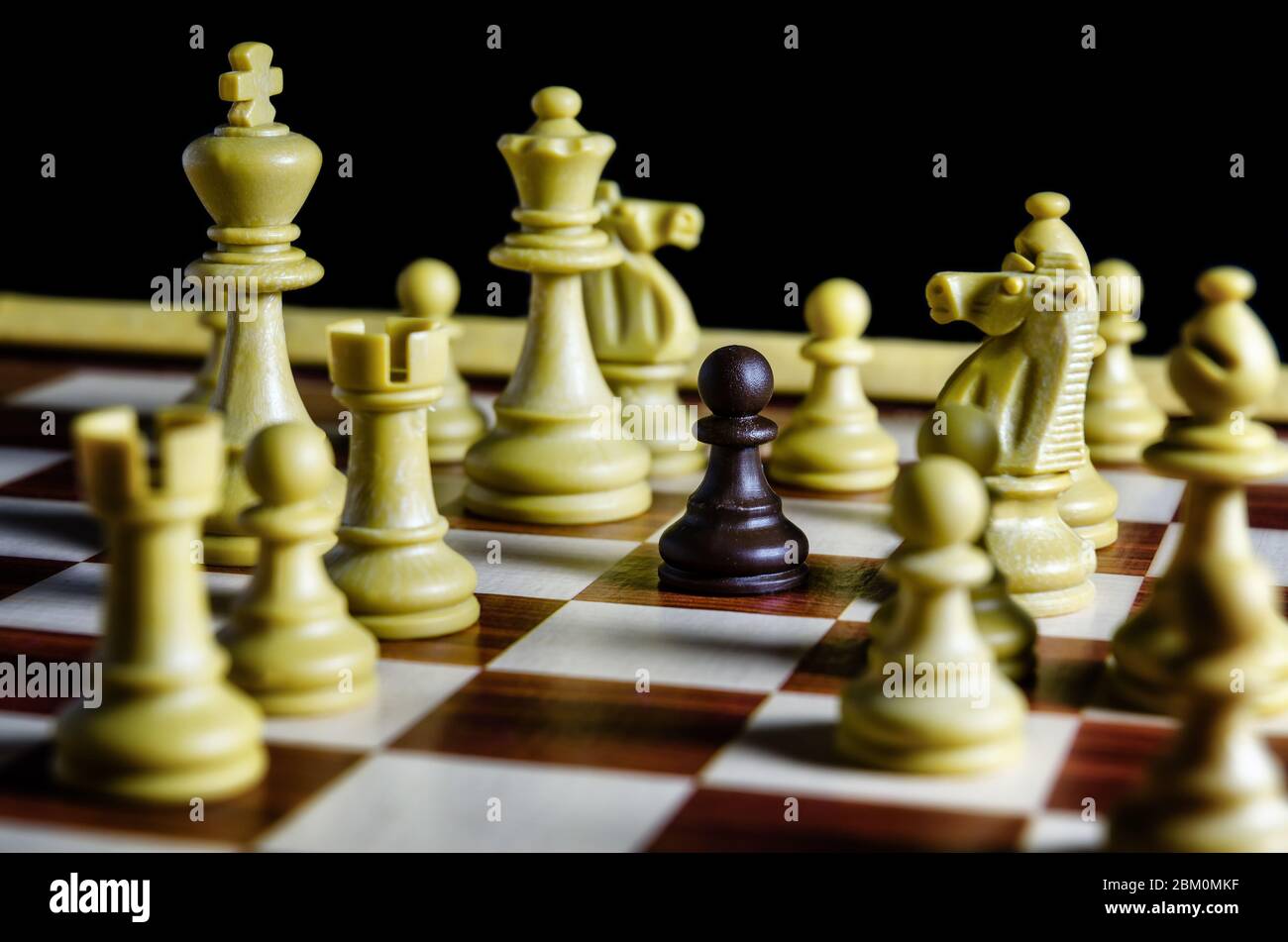 Black pawn on a chess board alone against all white pieces Stock Photo ...