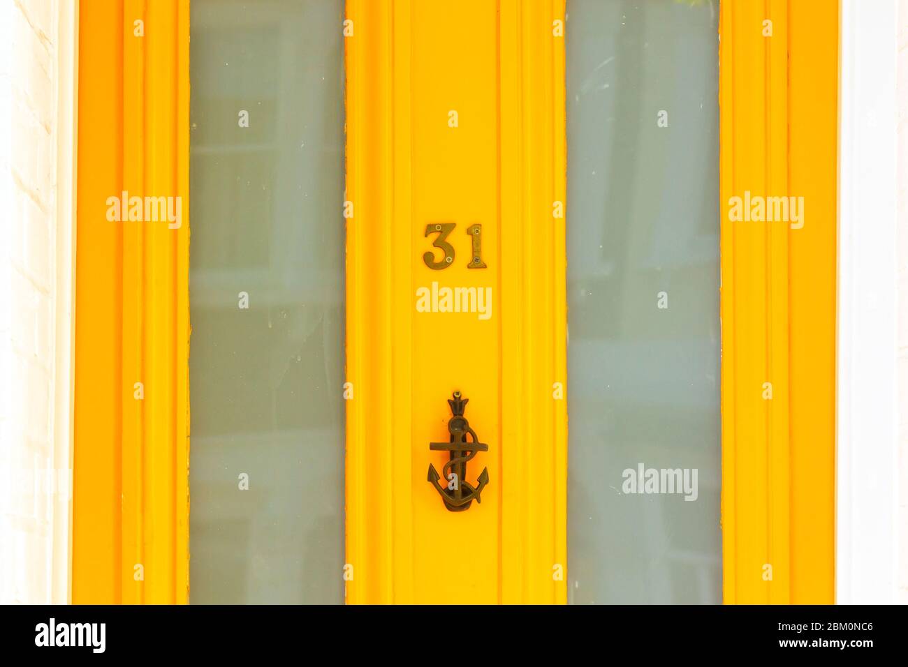 House number 31 on a bright orange wooden front door with glass and an ...