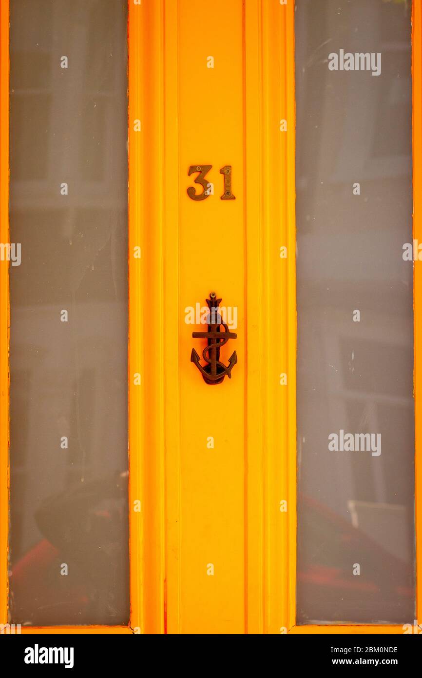 House number 31 on a bright orange wooden front door with glass and an ...
