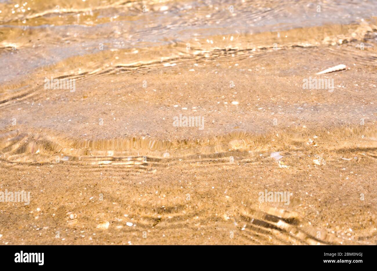 Reflection of sunlight on the moving sea water surface, sand beach and ...