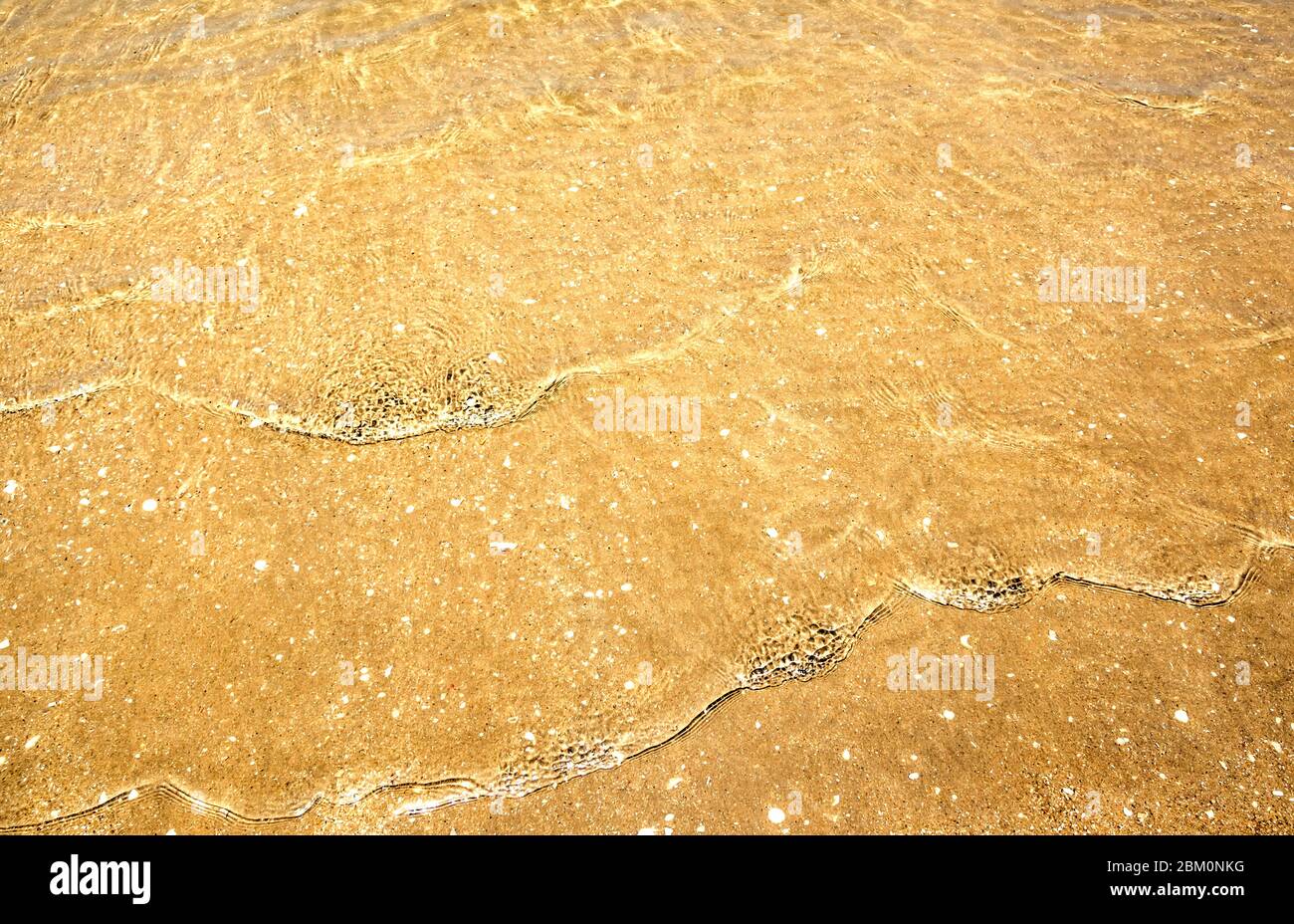 Reflection of sunlight on the moving sea water surface, sand beach and ...