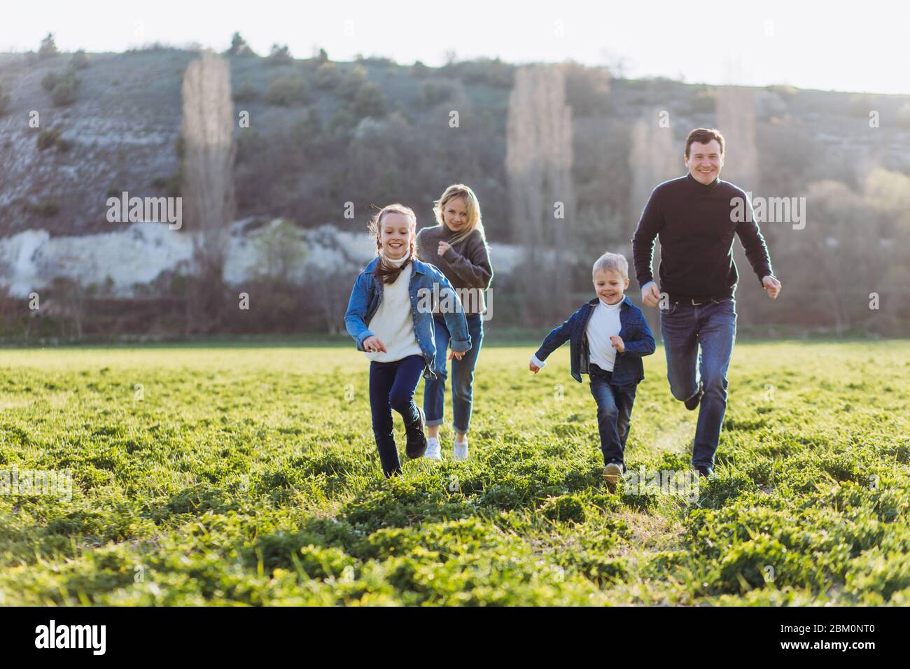 Happy family runs across the field. Father, mother and children run ...