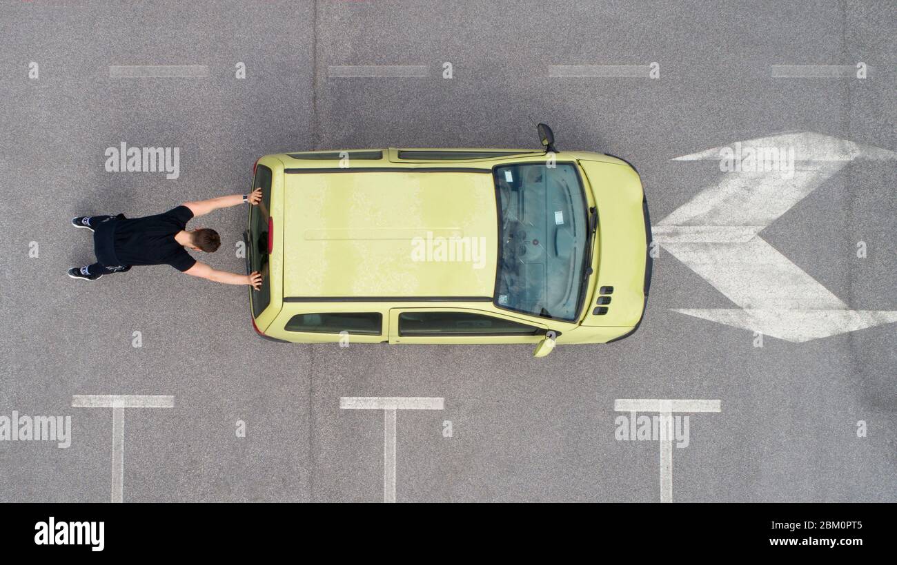 Strong man pushing a yellow car Stock Photo - Alamy