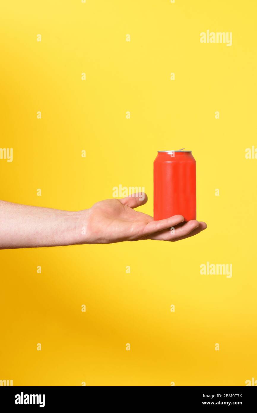 man holding a can on yellow background Stock Photo - Alamy