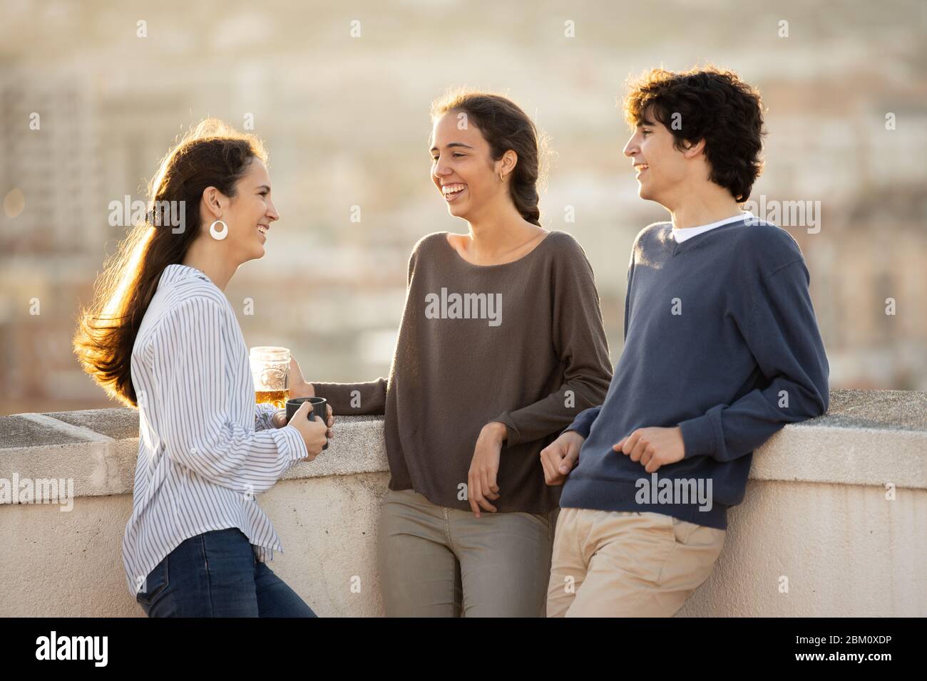 Three happy brothers talking and drinking on the rooftop Stock Photo ...