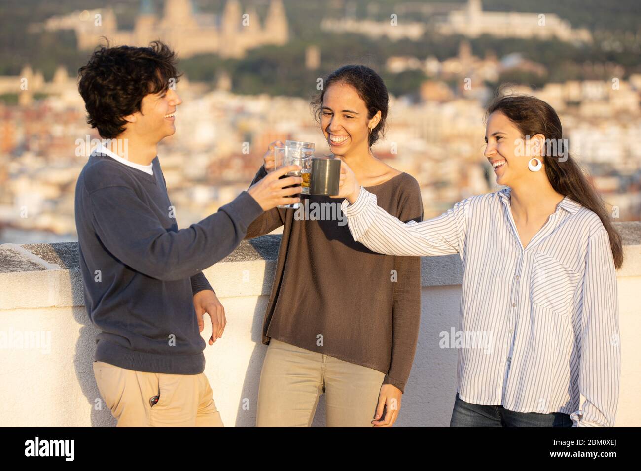 Three young people laughing and making a toast outdoors Stock Photo - Alamy