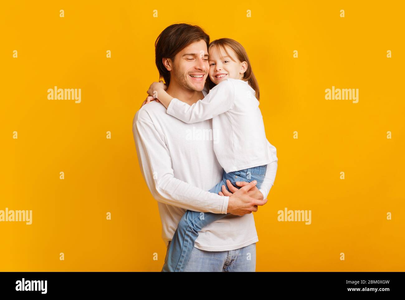 Positive father and daughter posing together on yellow background Stock ...