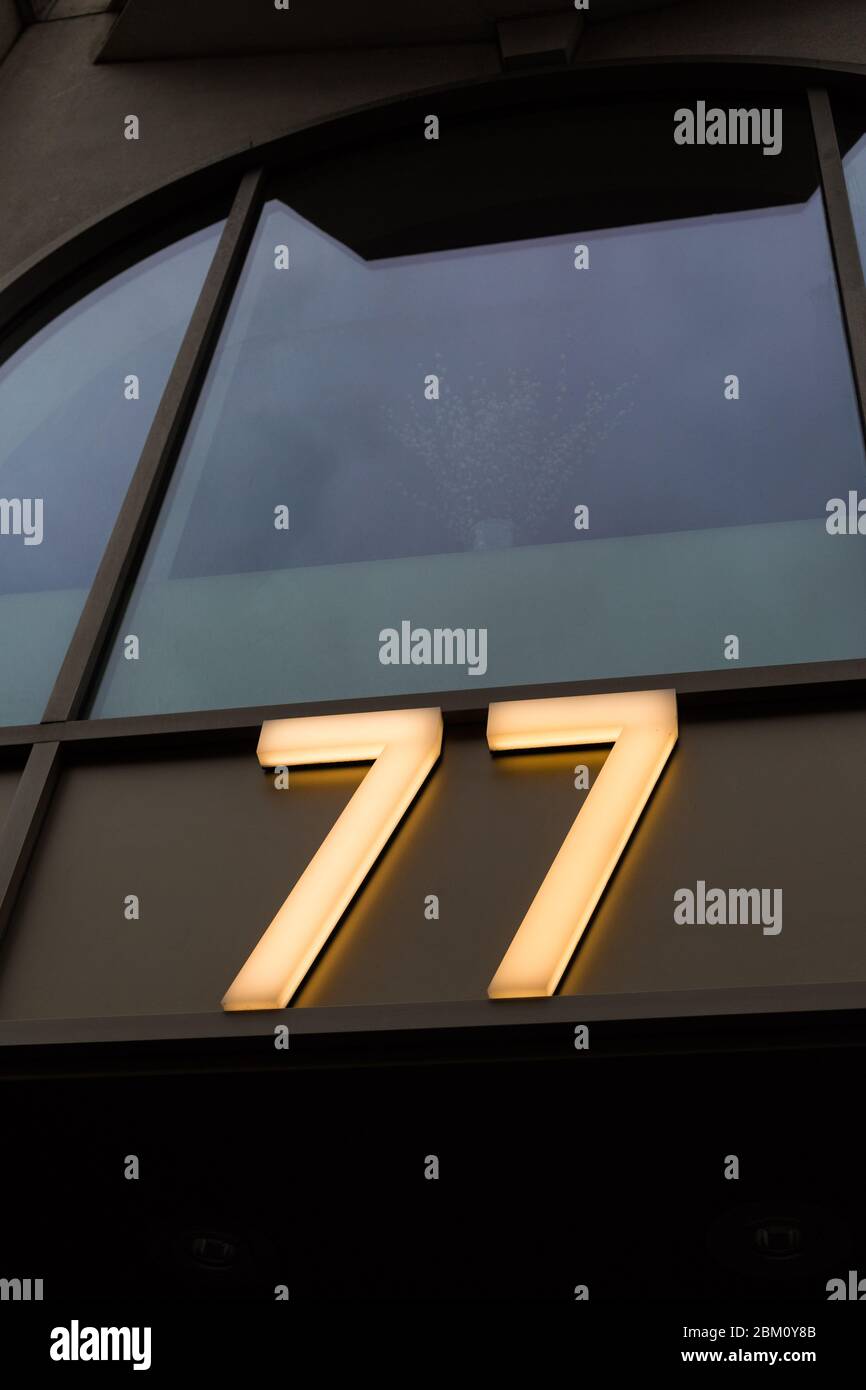 Bright and bold number 77 (seventy-seven) on the front of a building ...
