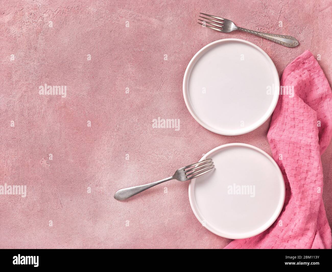 Two empty dessert plates, forks and napkin on pink concrete background ...