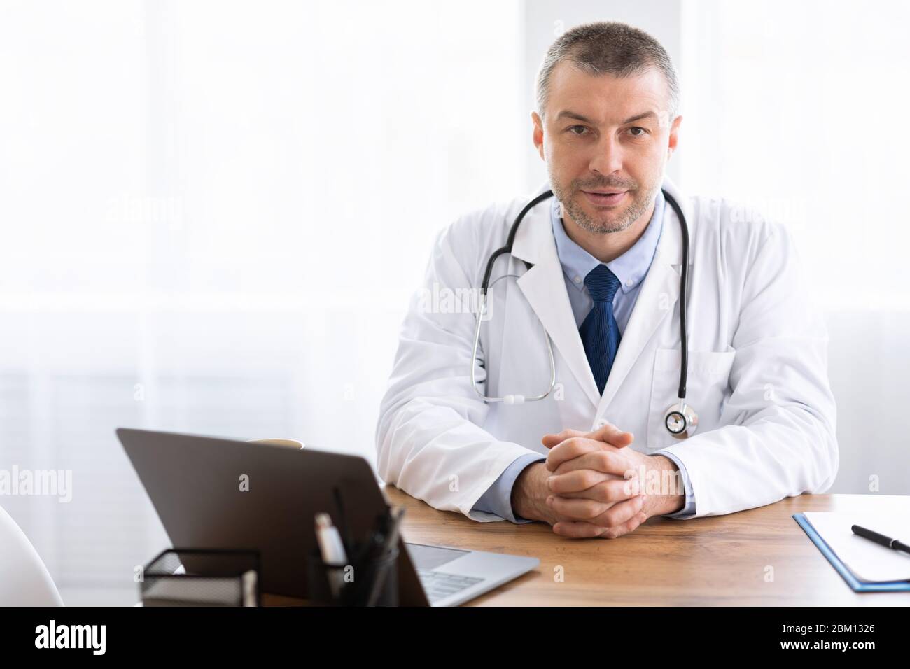 Portrait senior physician sitting desk hi-res stock photography and ...