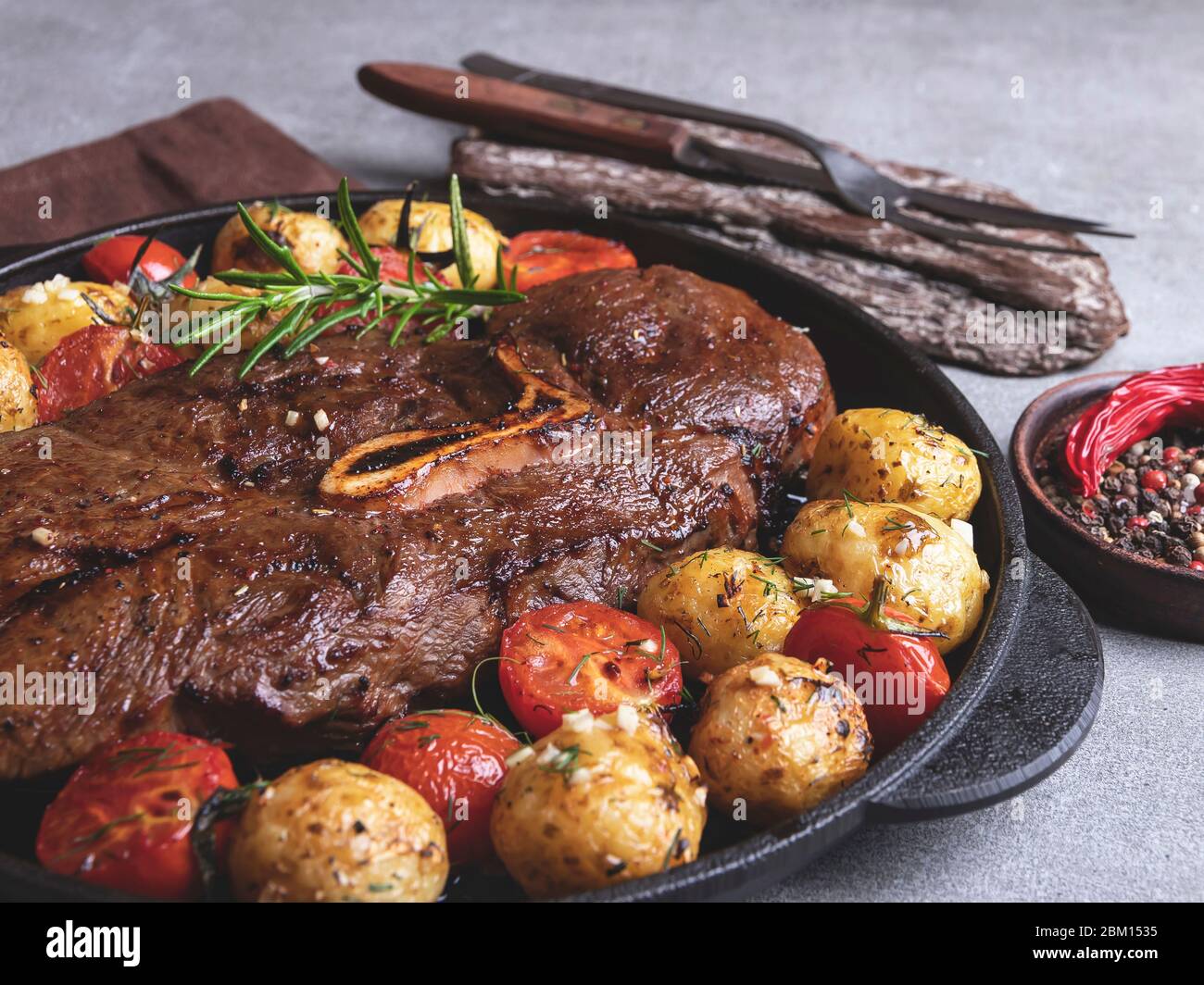 grilled beef steak with bone, roasted new potatoes tomato with garlic ...