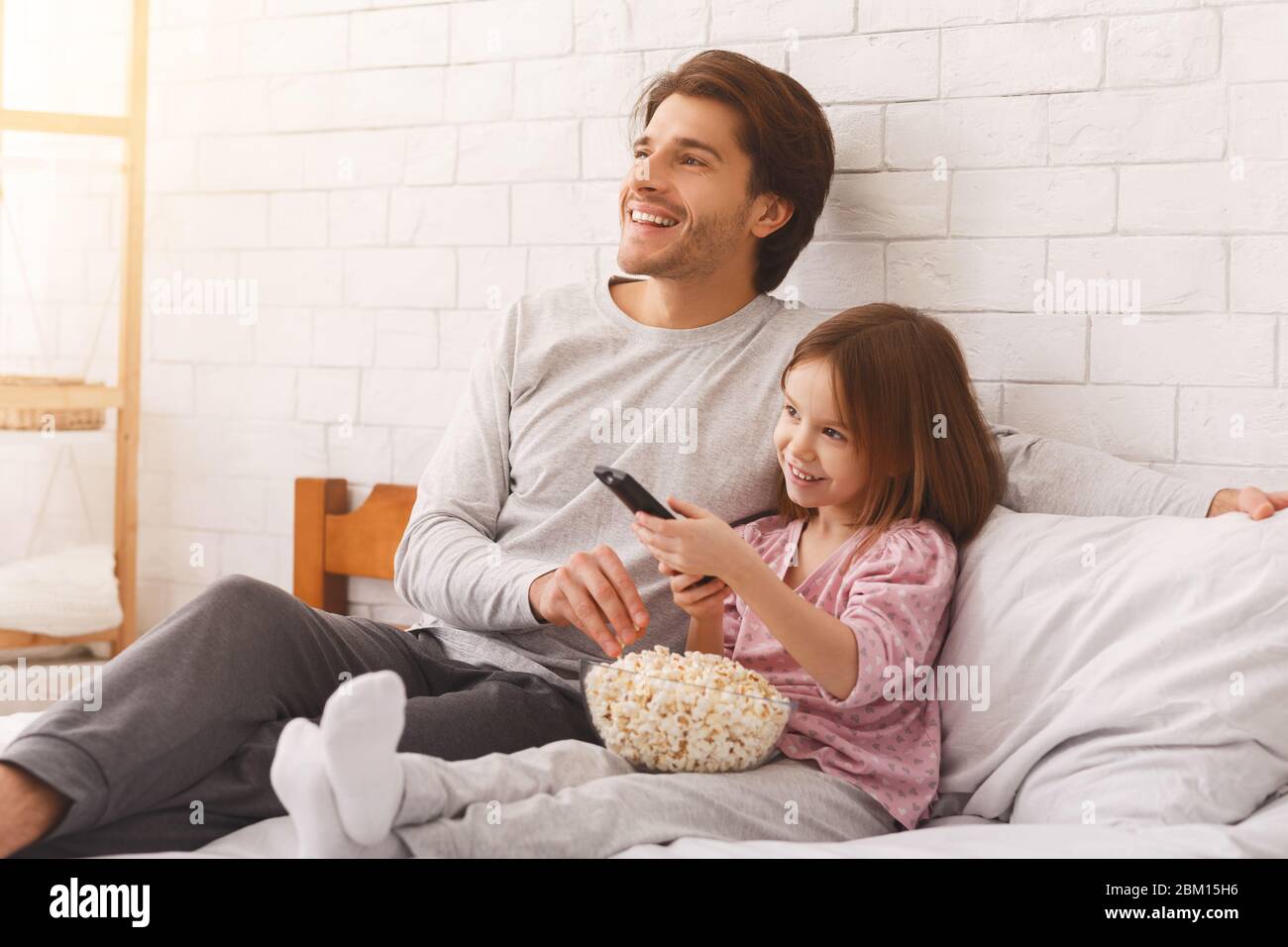 Girl watching TV with her young dad, eating popcorn Stock Photo - Alamy