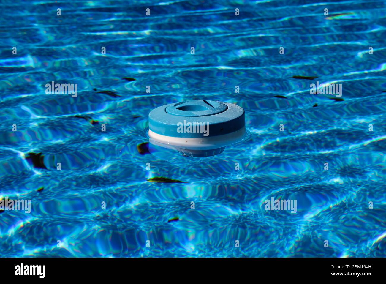 Crystal clear bright blue chlorine distributor lazily floating in the ...