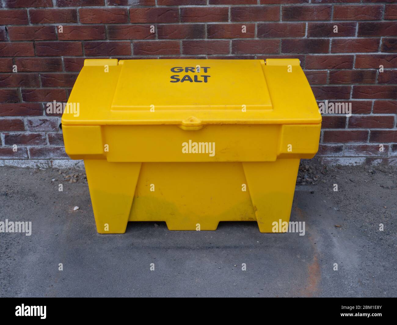 Yellow Salt Grit bin with brick wall background Stock Photo - Alamy