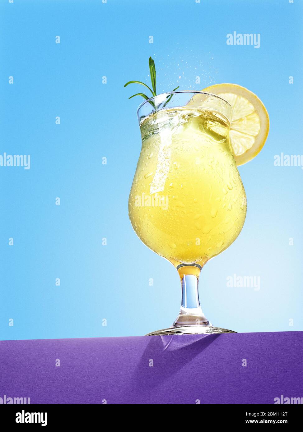 Glass of yellow lemon spritzer cocktail with rosemary on blue ...