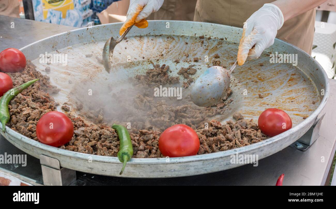Traditional Turkish shawarma meat being prepared with red tomatoes and ...
