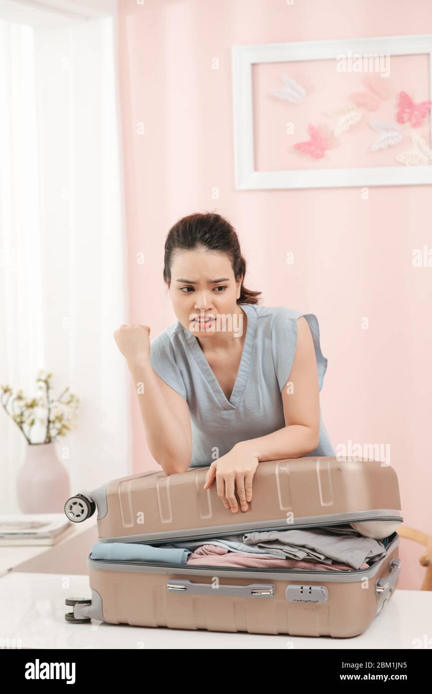 Girl packing for travel, closing hardly overflowing luggage bag Stock ...