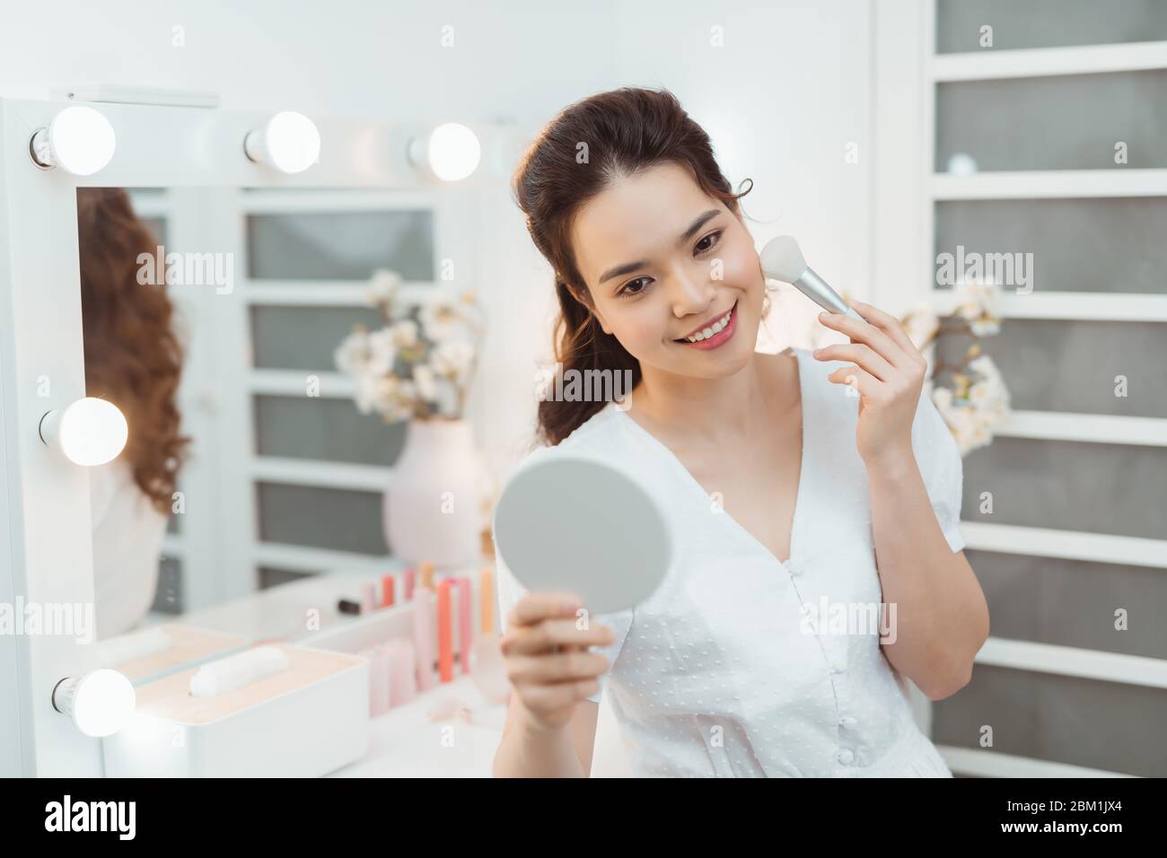 Beauty model girl applying makeup and smiling. Beautiful young woman ...